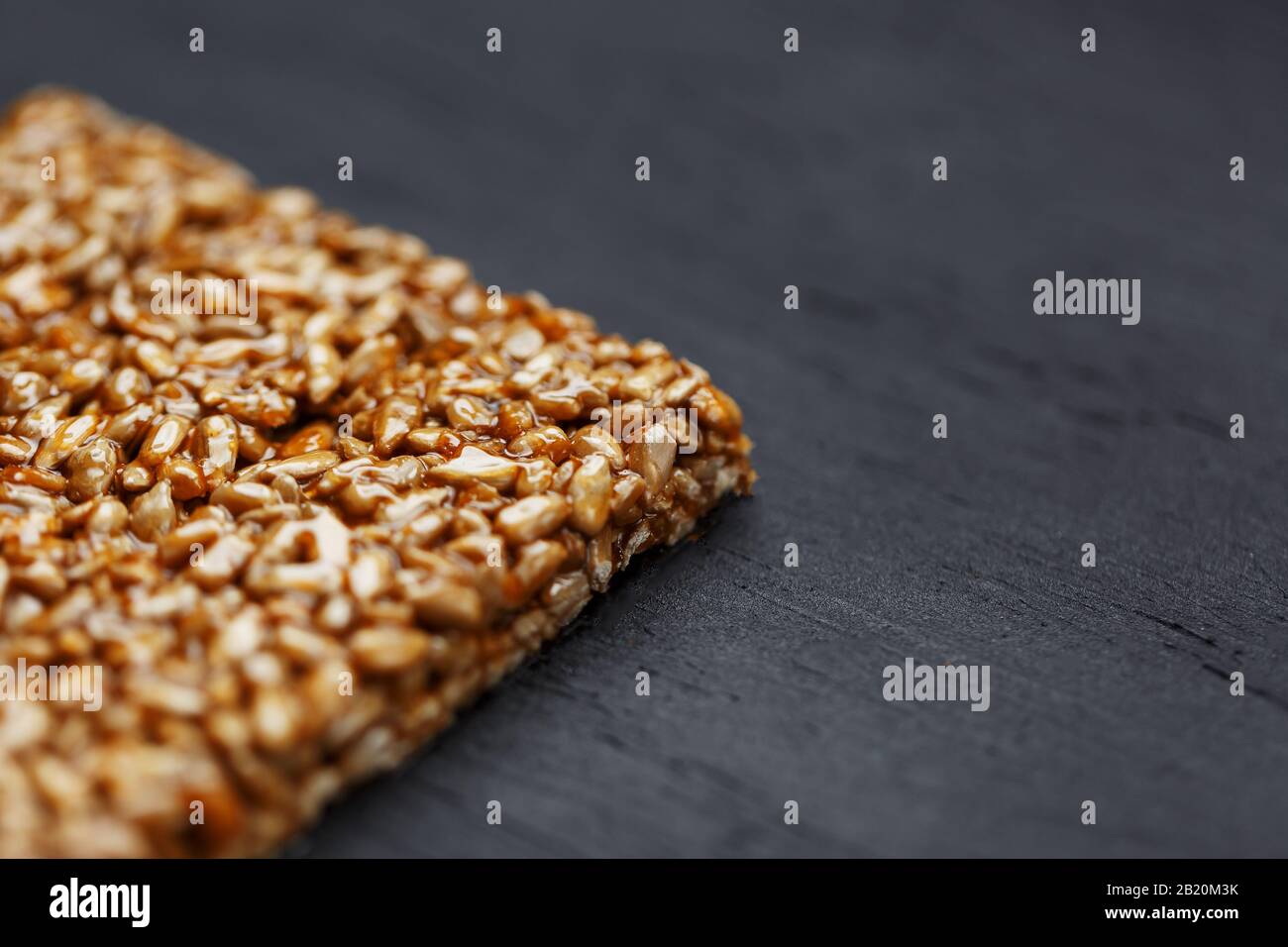 Tile kozinaki from sunflower seeds on a black textural background ...