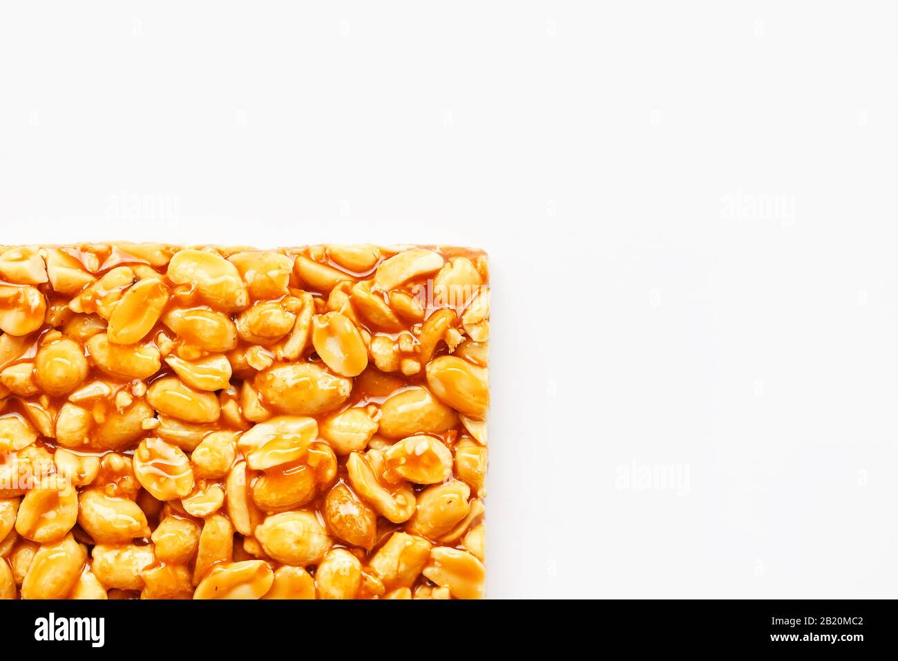 A large tile of roasted peanuts bar in a sweet molasses on a white ...