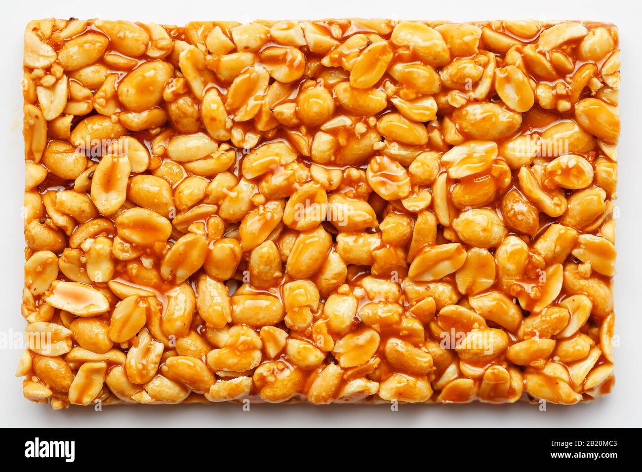 A large tile of roasted peanuts bar in a sweet molasses on a white ...