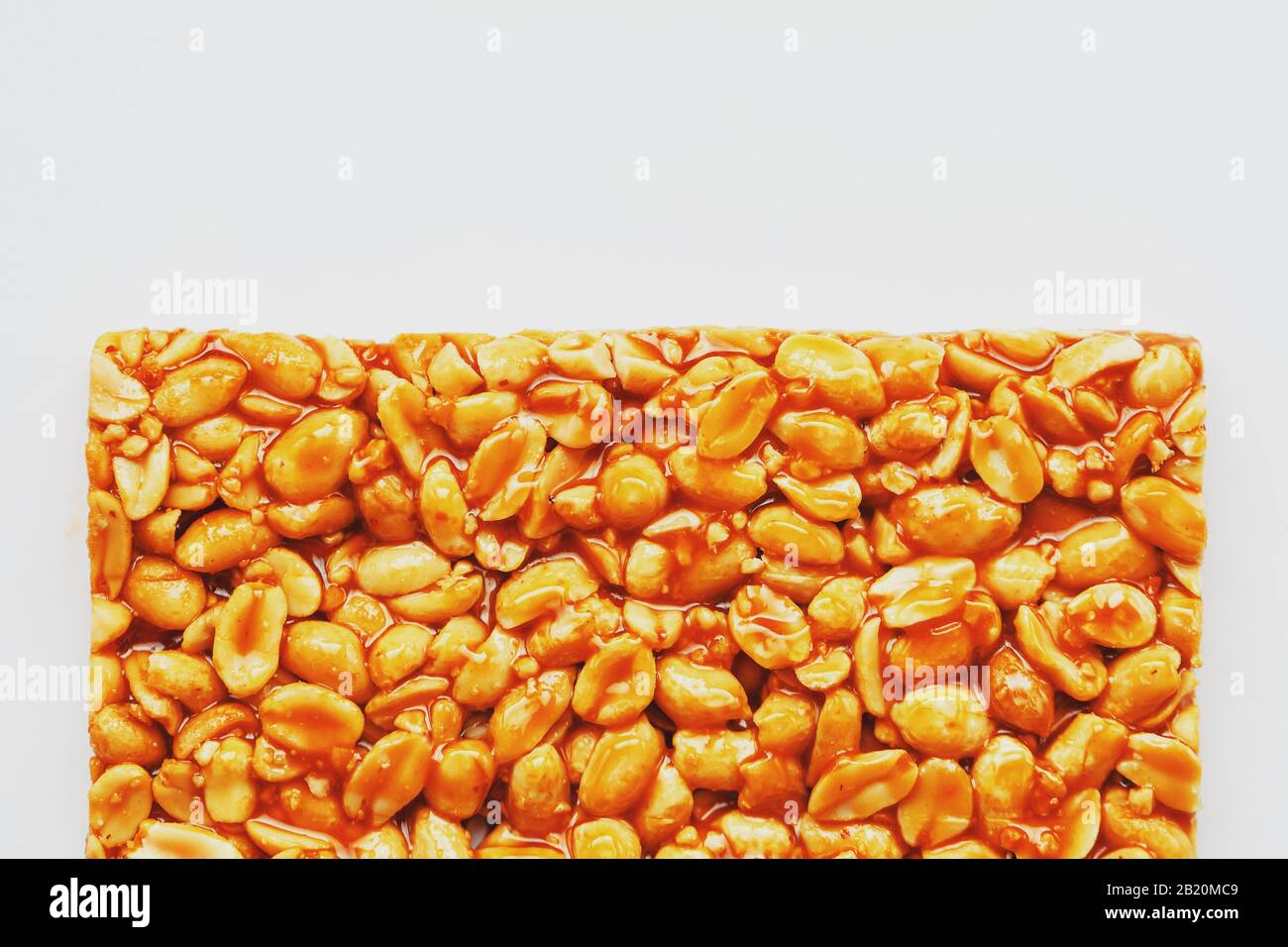 A large tile of roasted peanuts bar in a sweet molasses on a white ...