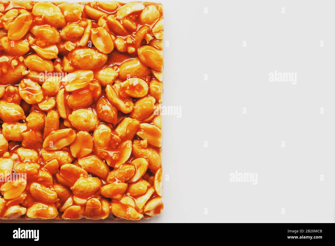 A large tile of roasted peanuts bar in a sweet molasses on a white ...