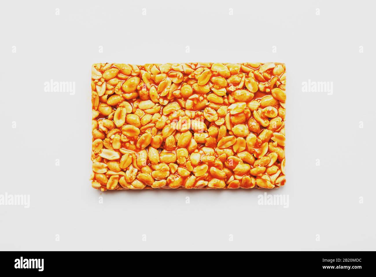 A large tile of roasted peanuts bar in a sweet molasses on a white ...