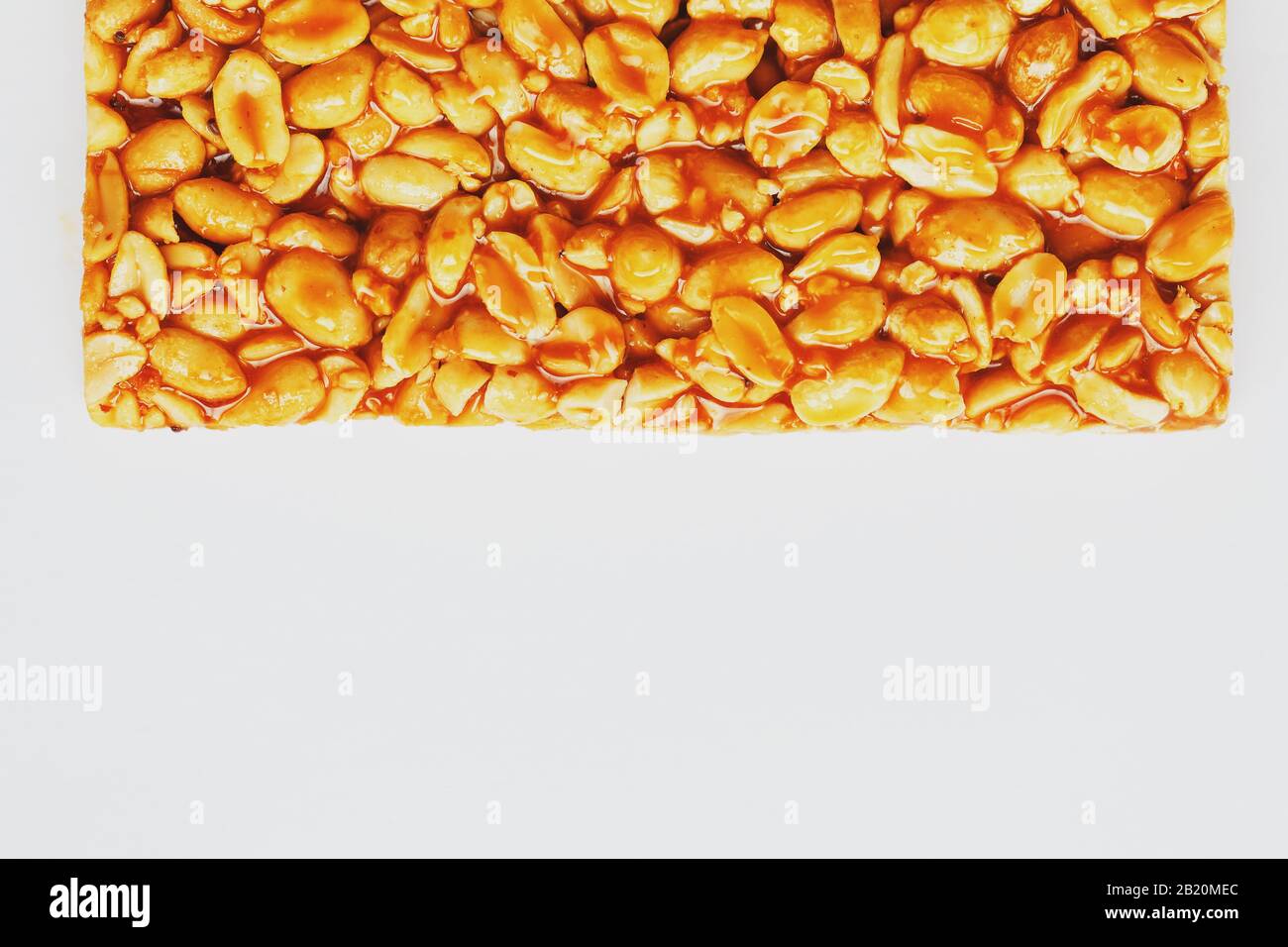 A large tile of roasted peanuts bar in a sweet molasses on a white ...