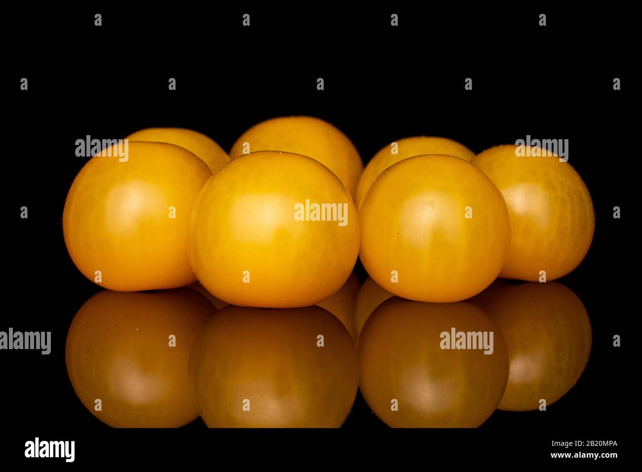 Group of seven whole fresh yellow tomato isolated on black glass Stock ...