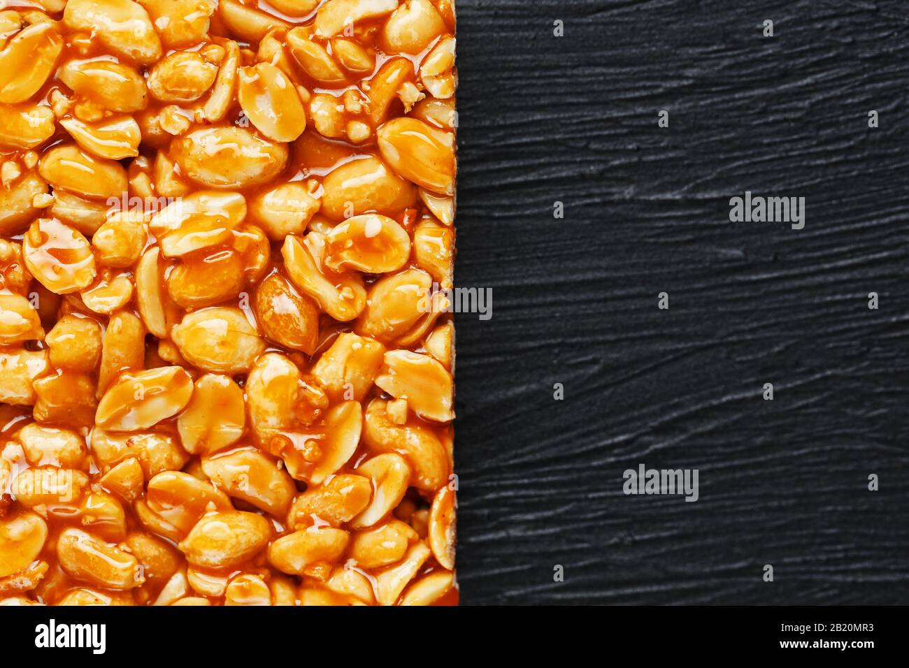 A large golden tile of peanuts, a bar in a sweet molasses on a black ...