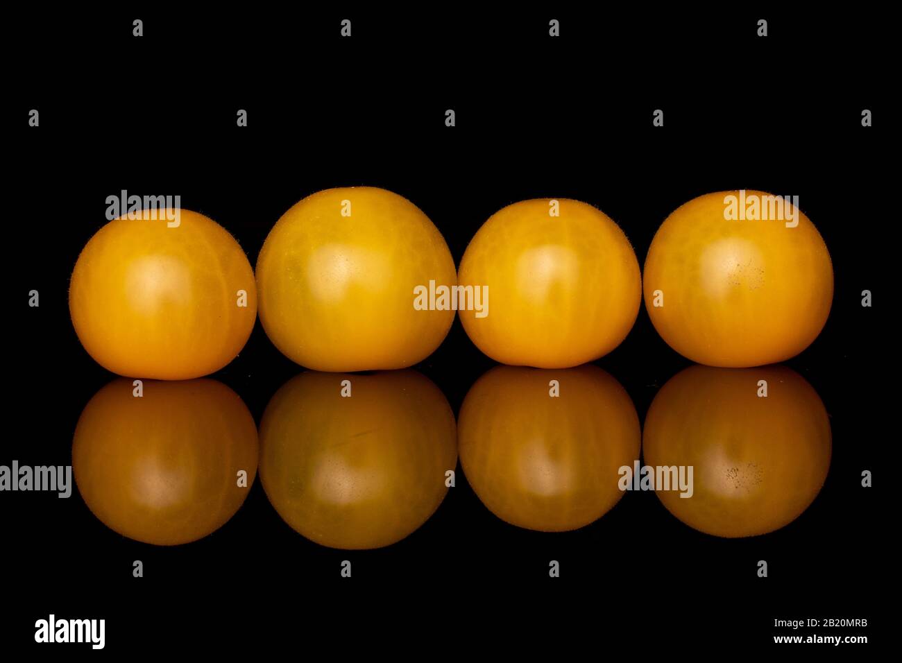 Group of four whole fresh yellow tomato isolated on black glass Stock ...
