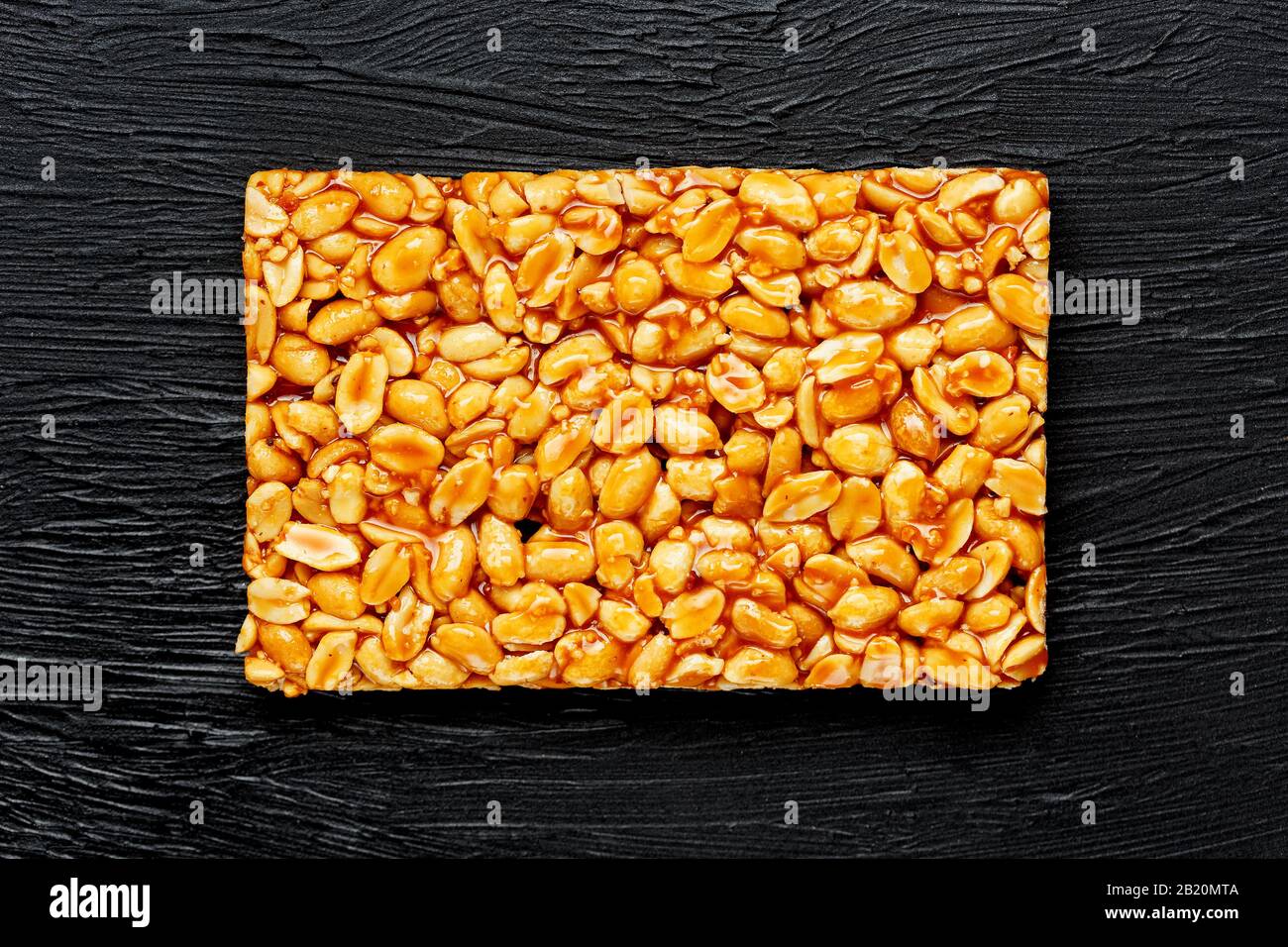 A large golden tile of peanuts, a bar in a sweet molasses on a black ...