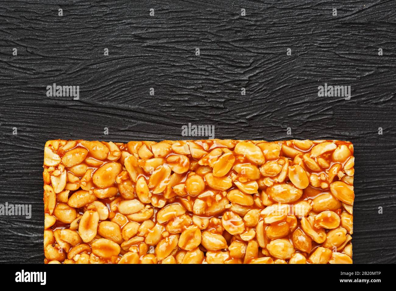 A large golden tile of peanuts, a bar in a sweet molasses on a black ...