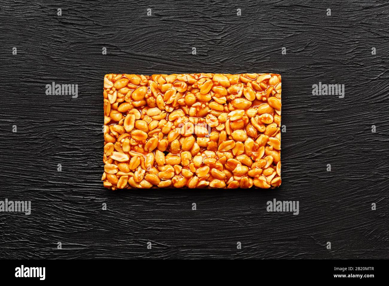 A large golden tile of peanuts, a bar in a sweet molasses on a black ...