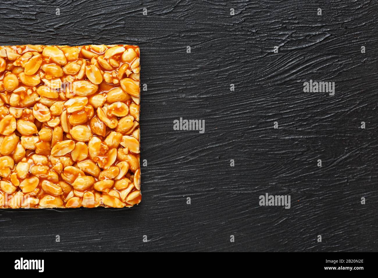 A large golden tile of peanuts, a bar in a sweet molasses on a black ...