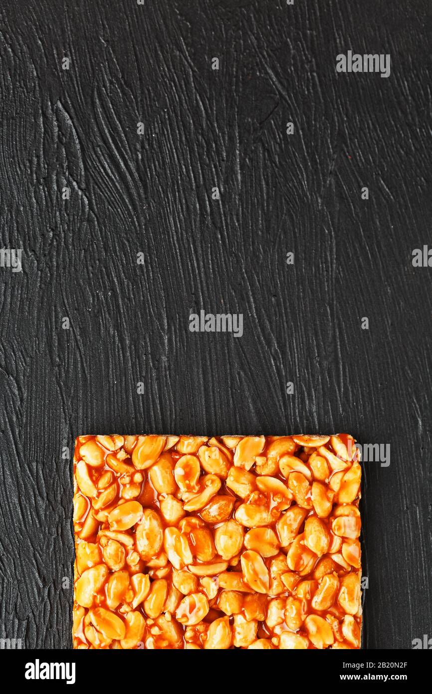 A large golden tile of peanuts, a bar in a sweet molasses on a black ...