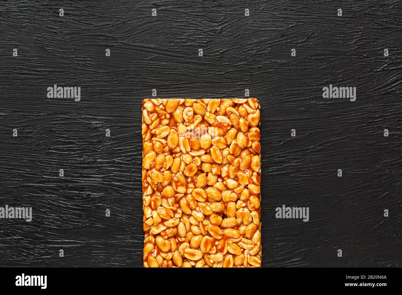 A large golden tile of peanuts, a bar in a sweet molasses on a black ...