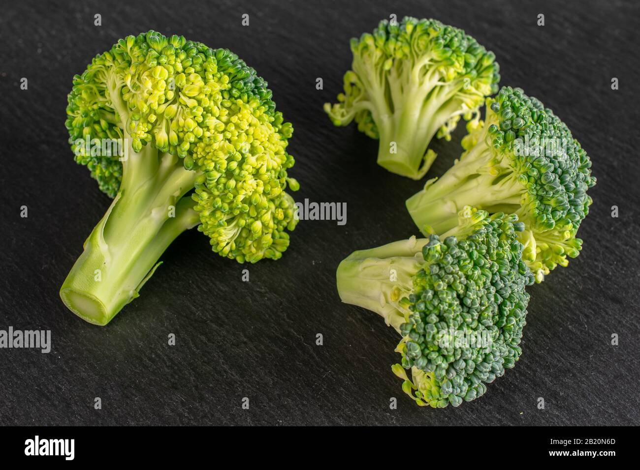 Group of four whole fresh green broccoli head on grey stone Stock Photo ...