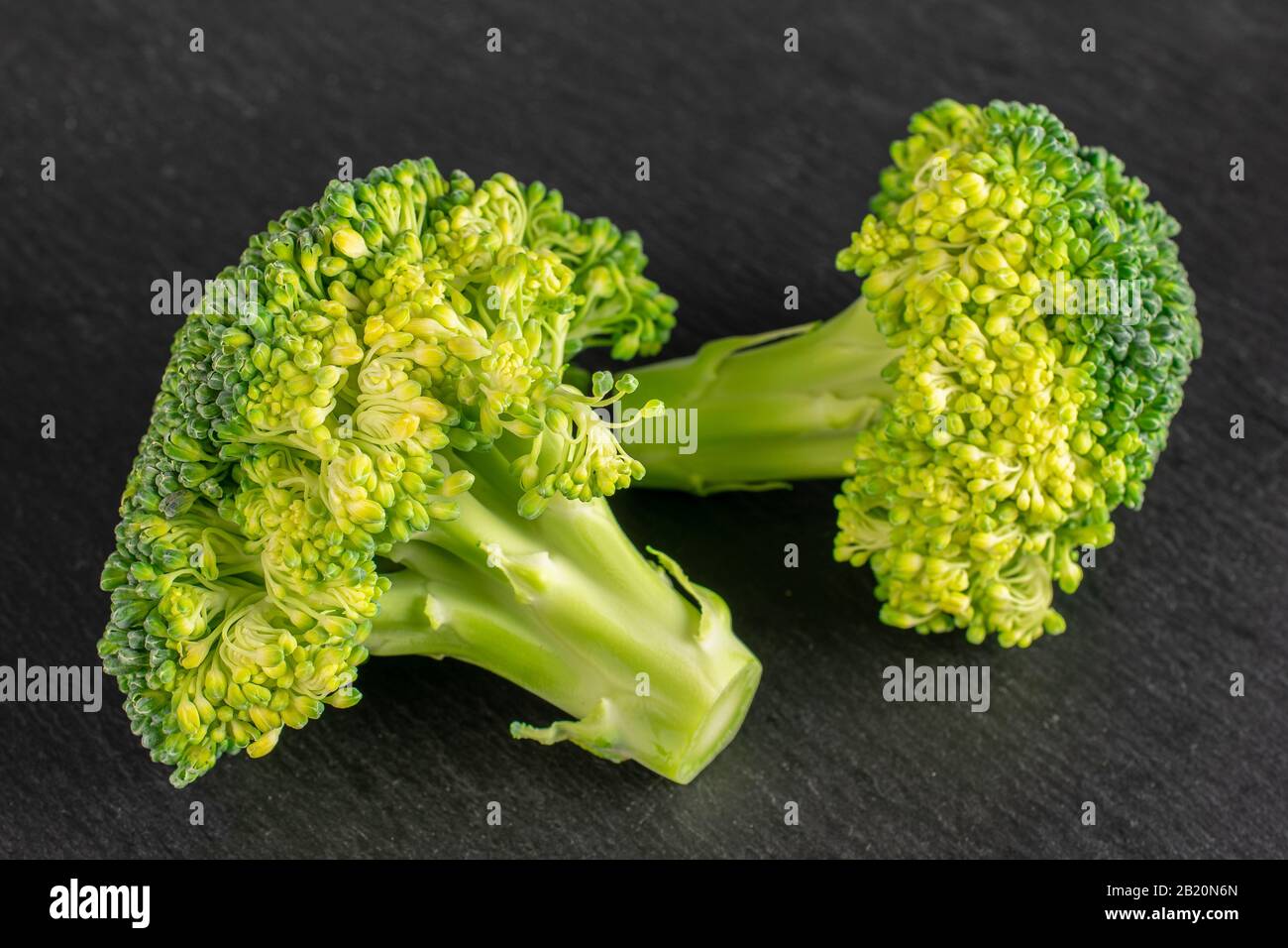 Group of two whole fresh green broccoli head on grey stone Stock Photo ...