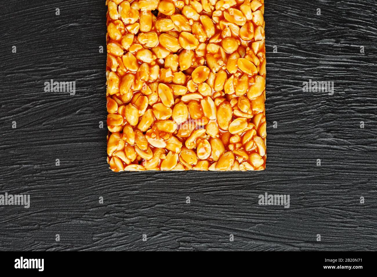 A large golden tile of peanuts, a bar in a sweet molasses on a black ...
