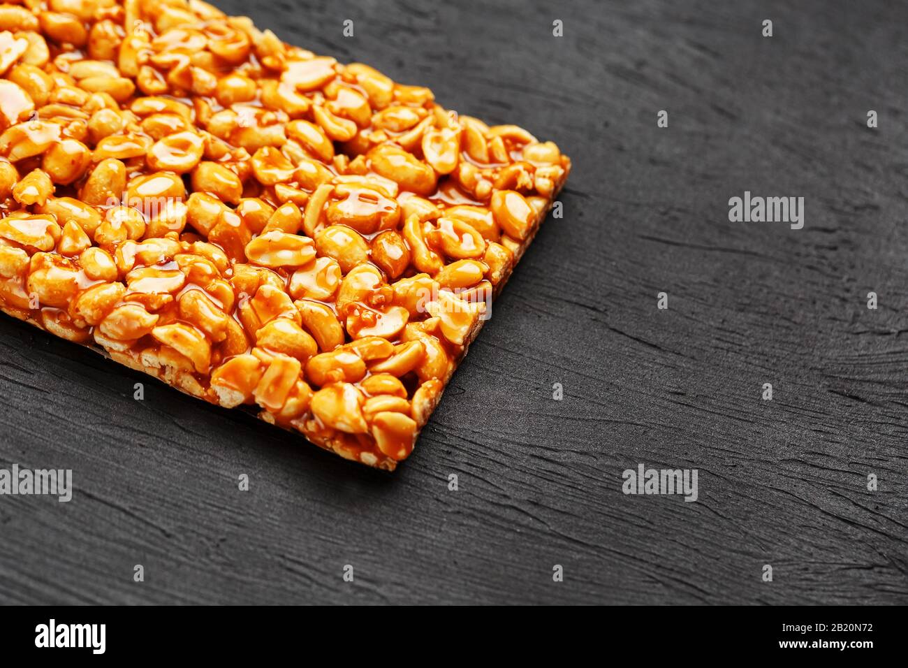 A large golden tile of peanuts, a bar in a sweet molasses on a black ...