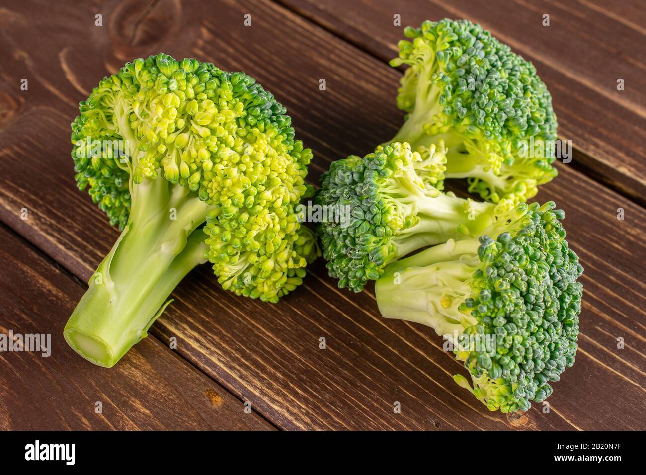 Group of four whole fresh green broccoli head on brown wood Stock Photo ...