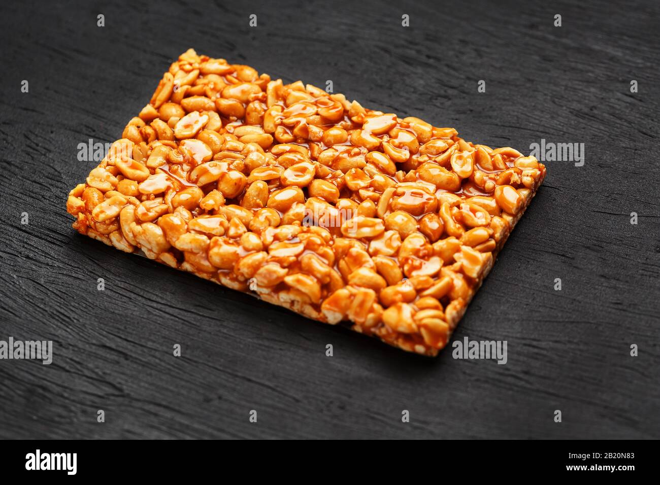 A large golden tile of peanuts, a bar in a sweet molasses on a black ...