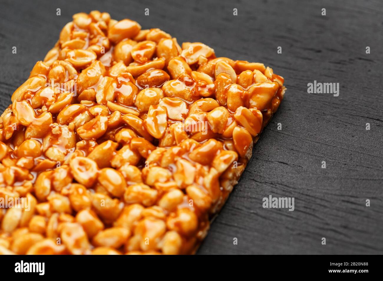 A large golden tile of peanuts, a bar in a sweet molasses on a black ...