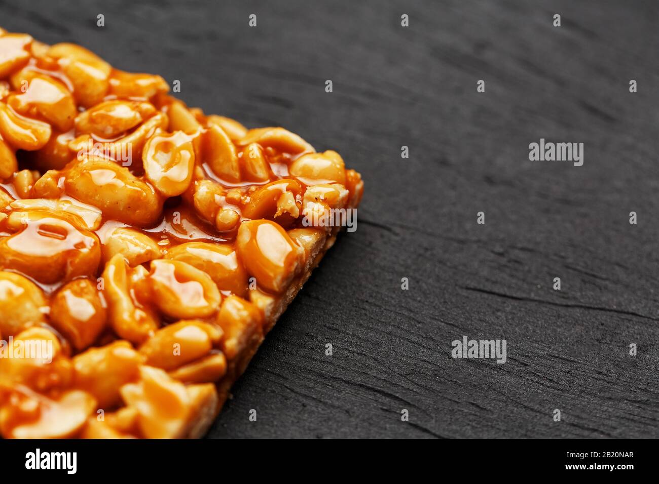 A large golden tile of peanuts, a bar in a sweet molasses on a black ...