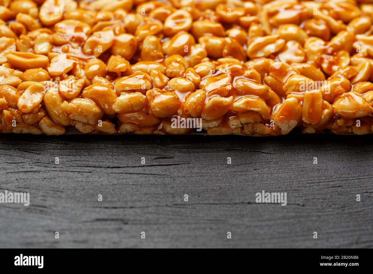 A large golden tile of peanuts, a bar in a sweet molasses on a black ...