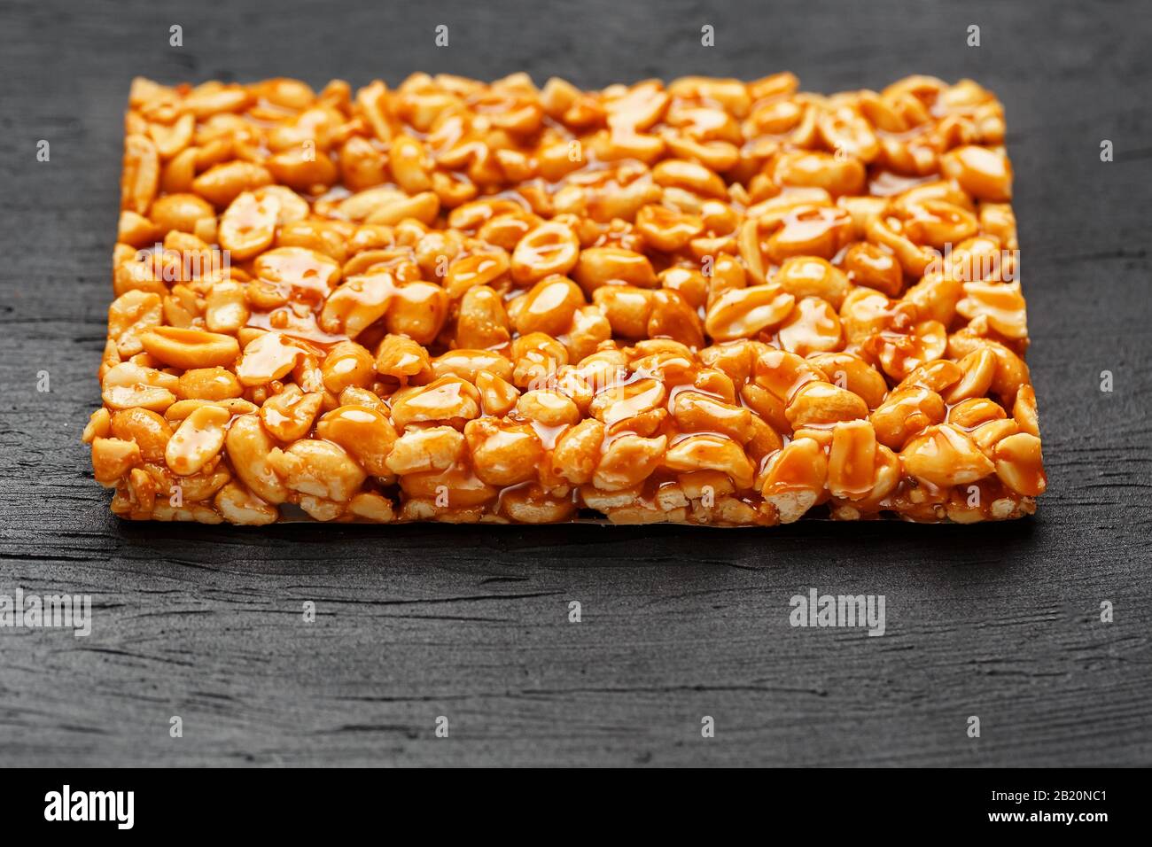 A large golden tile of peanuts, a bar in a sweet molasses on a black ...