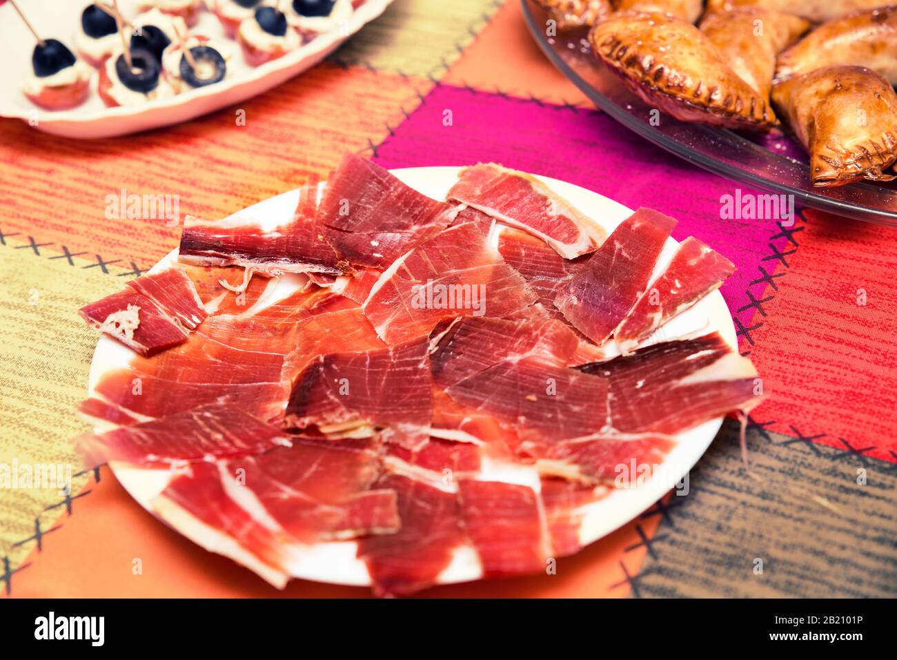 view of a white plate with messy slices of ham and appetizers with ...