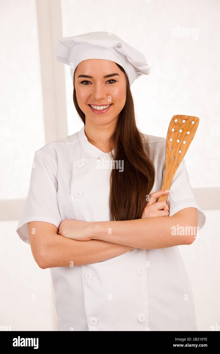 young blonde chef woamn holds kitchenware as she prepares to cook a ...