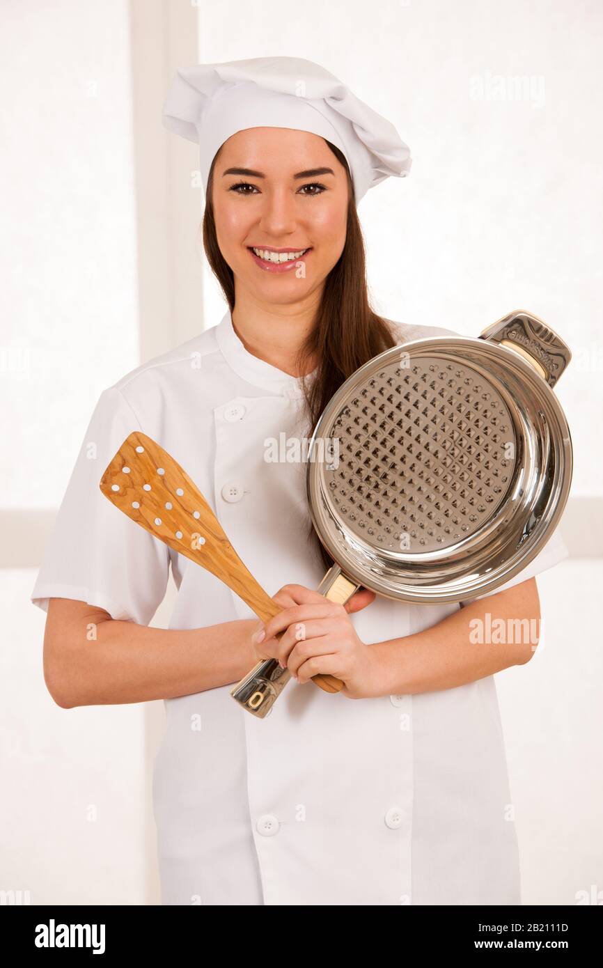 young blonde chef woamn holds kitchenware as she prepares to cook a ...