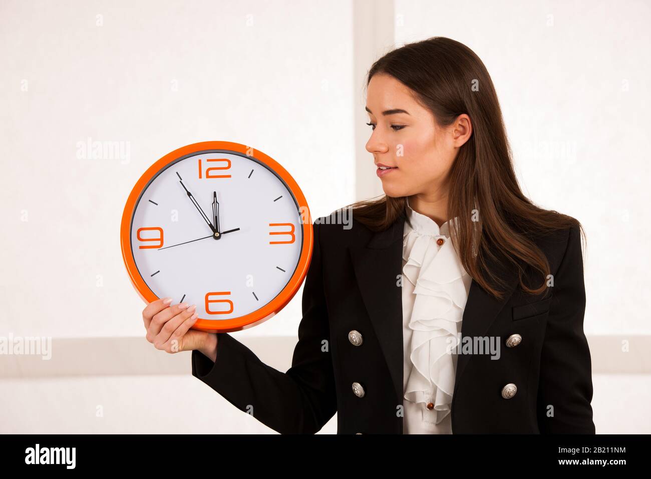 cute woman holding a clock as a symbol of time management Stock Photo ...