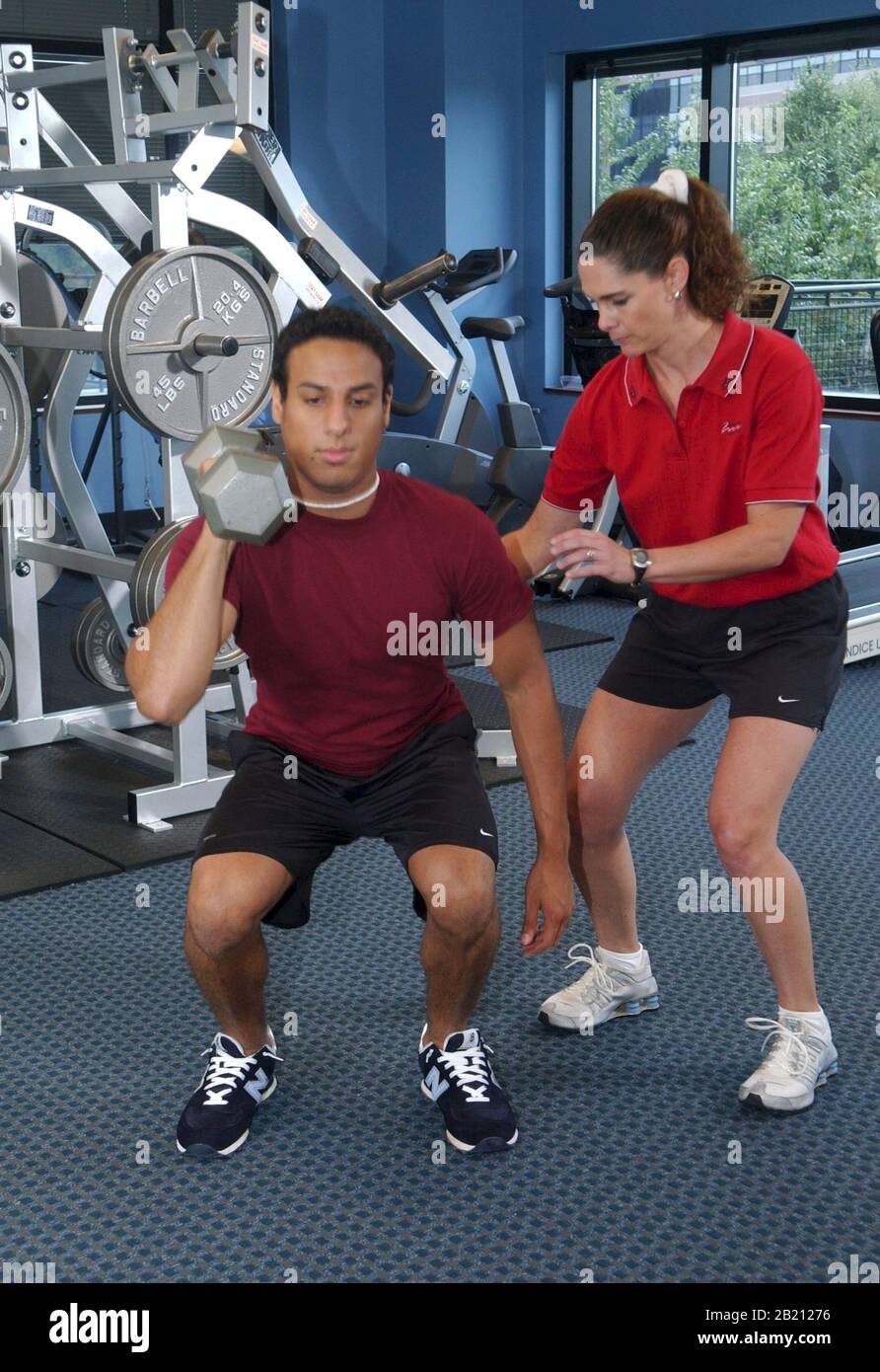 Austin, Texas - Hispanic teen (19) lifts weights with female personal ...