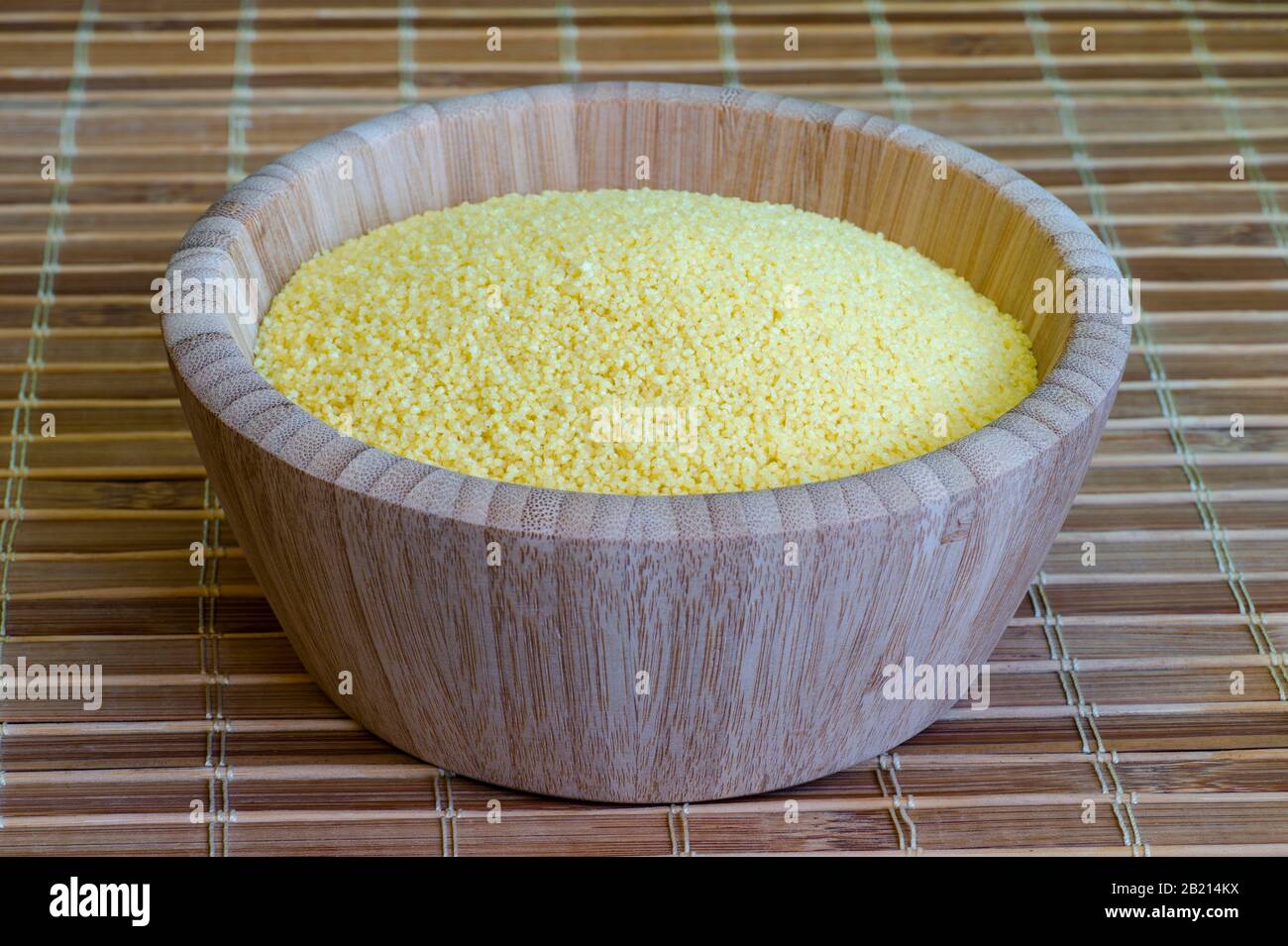 Dry couscous close-up in a wooden bowl on a bamboo stand. Concept of ...