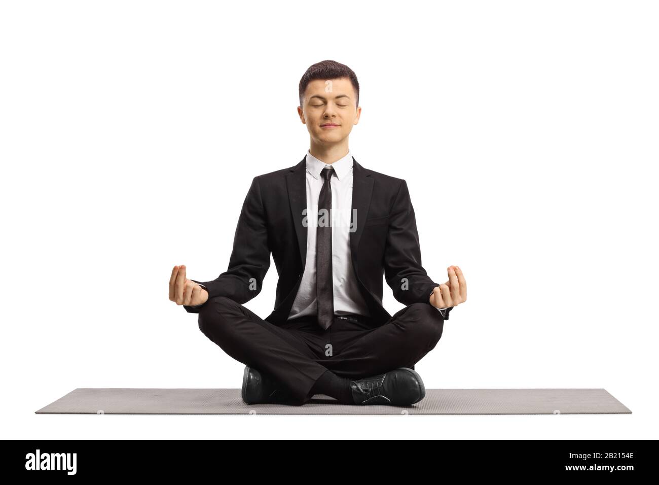 Young man in a black suit with closed eyes sitting with crossed legs ...