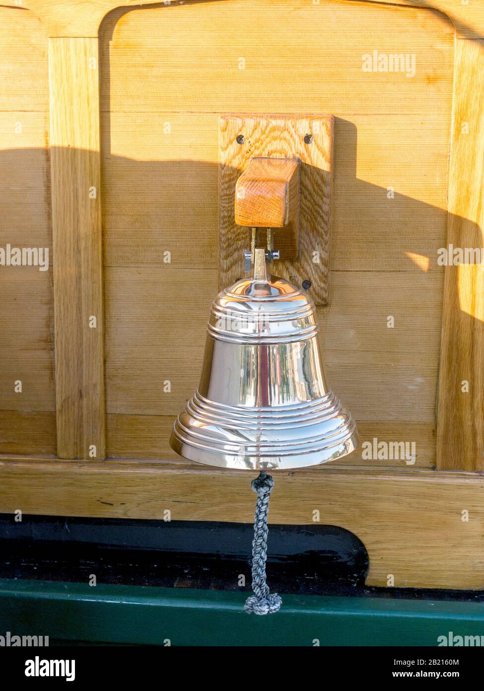 A beautiful brass bell is hanging on the decks of an antique tall ship ...