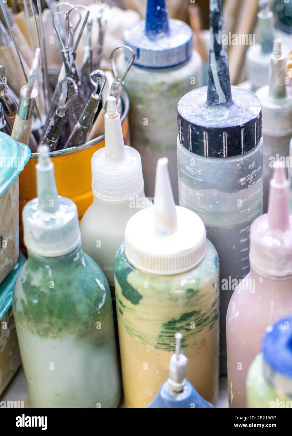 Containers filled with pottery glazes sit with carving tools in this ...