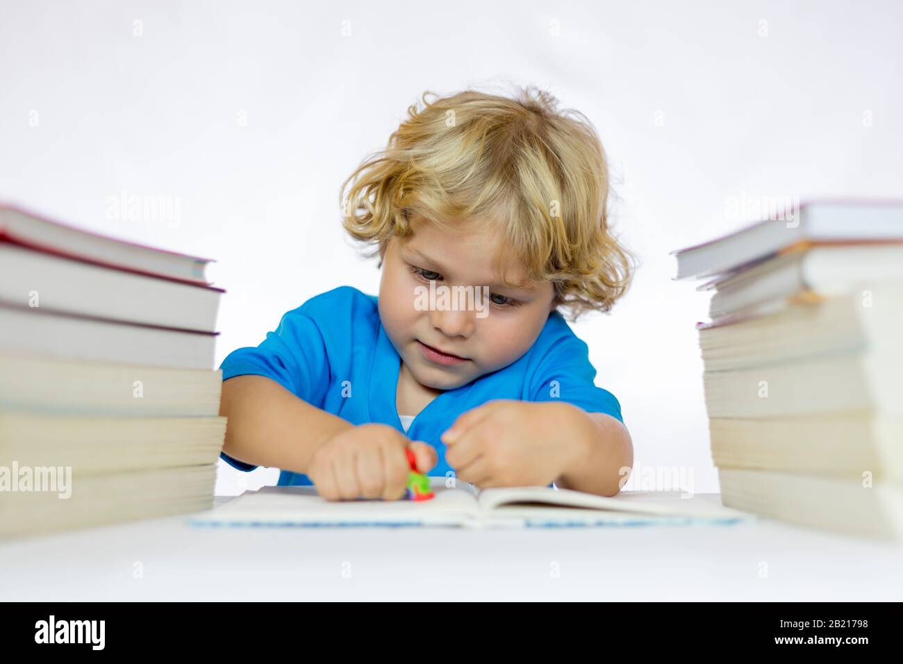 Little happy boy between 4 and 5 years old sitting at a desk doing his ...