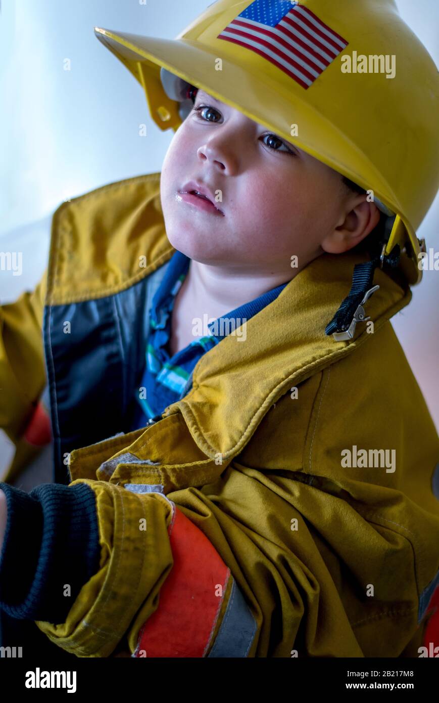A young boy dresses up in a firefighter costume complete with hard hat ...