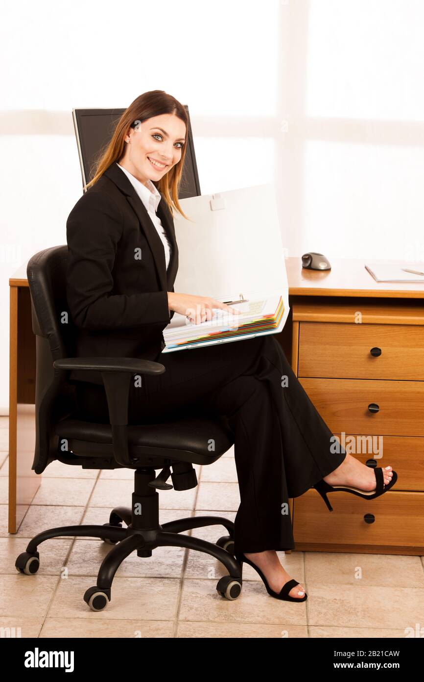 Young business woman with bold folder checking data at her desk in the ...