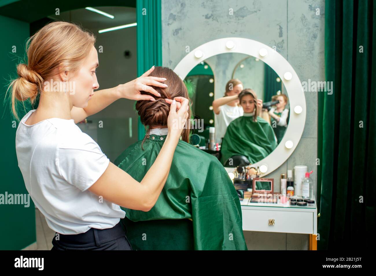 Professional hairdresser making hairstyle for woman in beauty salon ...