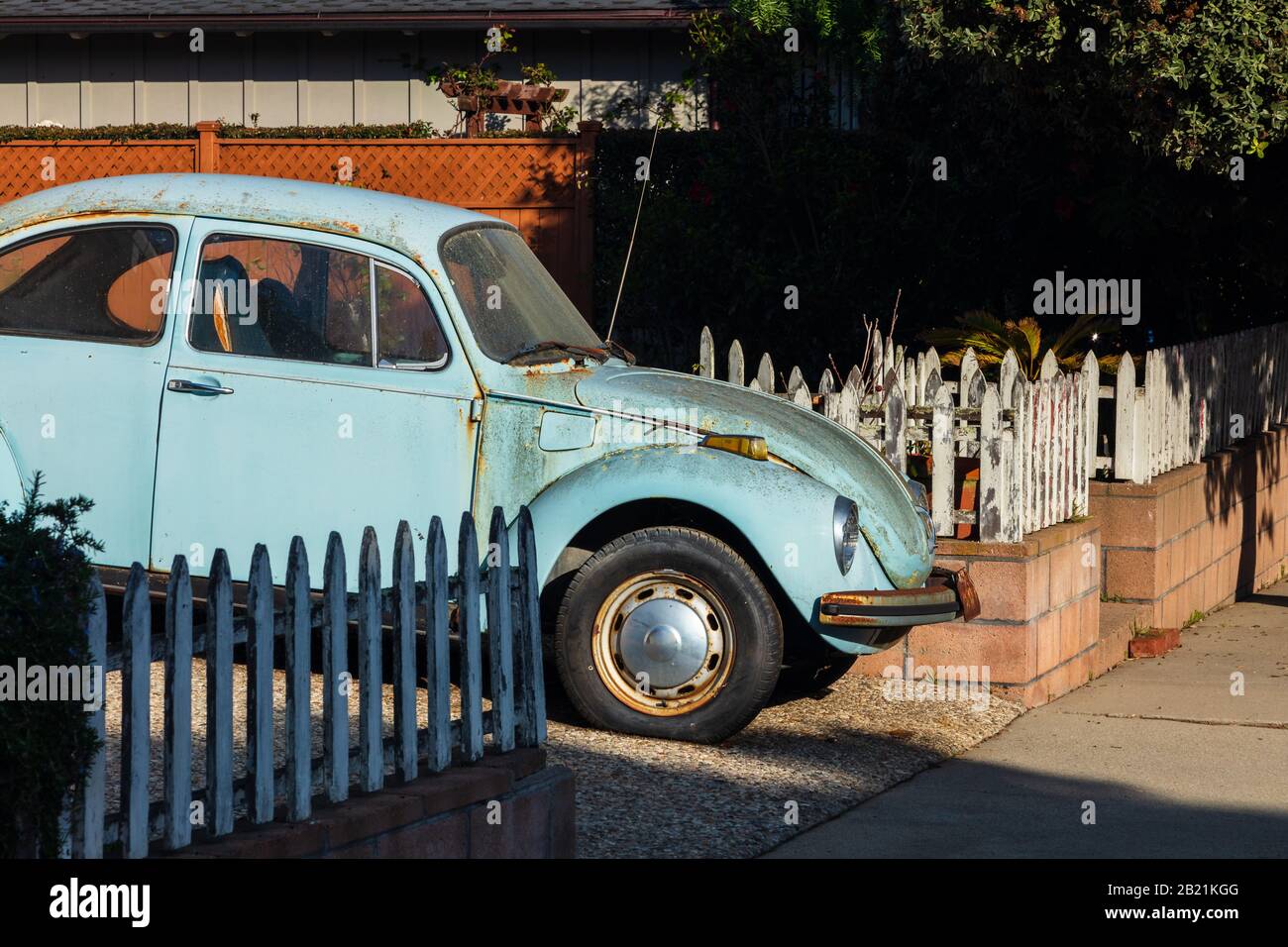 An old rusty and dirty car in a driveway sitting in the sun waiting for ...