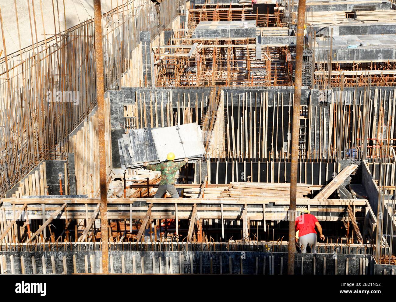 builder worker knitting metal rods bars into framework reinforcement ...