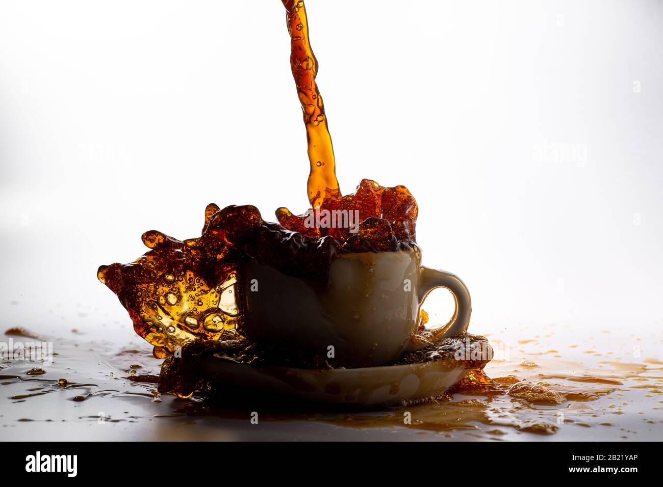Coffee pouring into a white cup isolated against a plain white ...