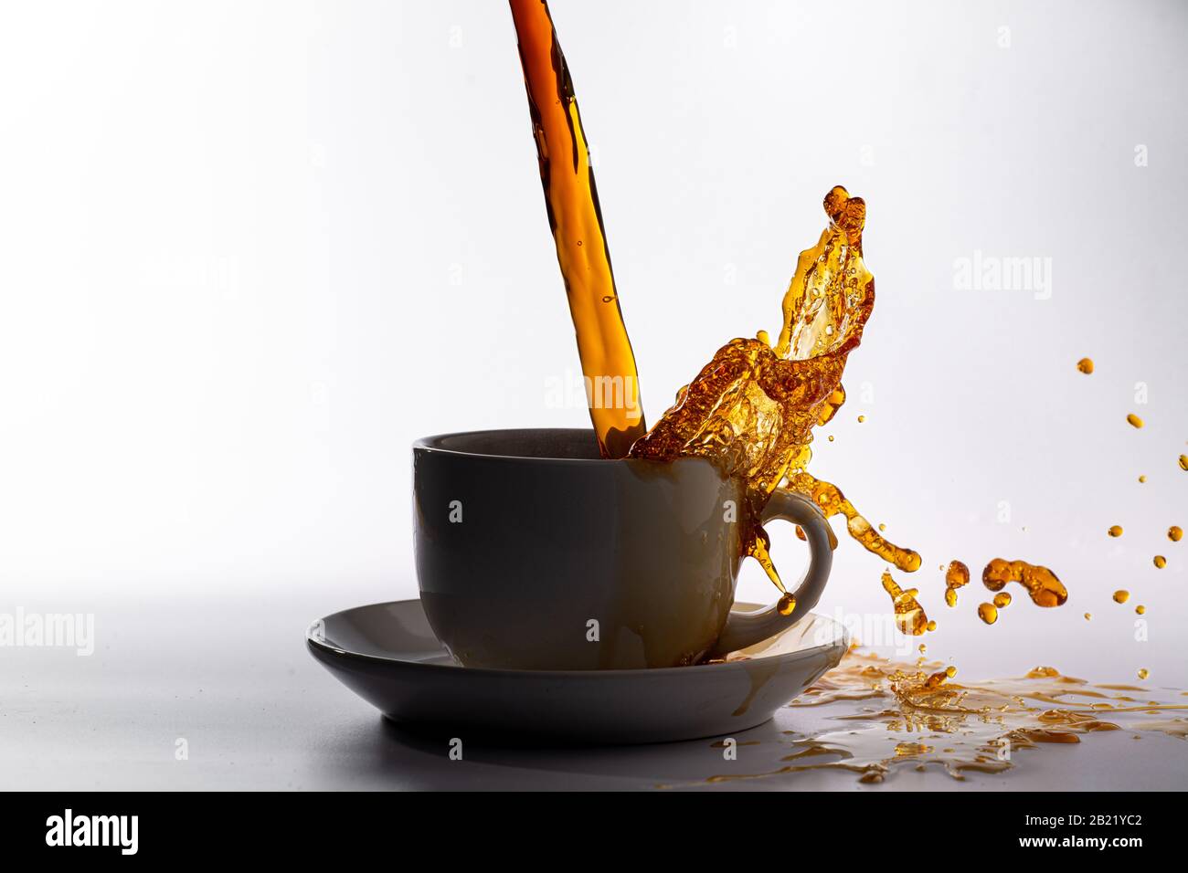 Coffee pouring into a white cup isolated against a plain white ...