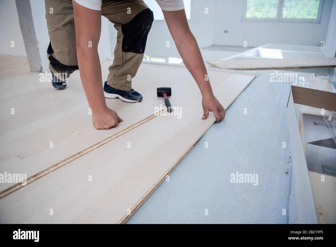 professional carpenter installing new laminated wooden floor in a ...