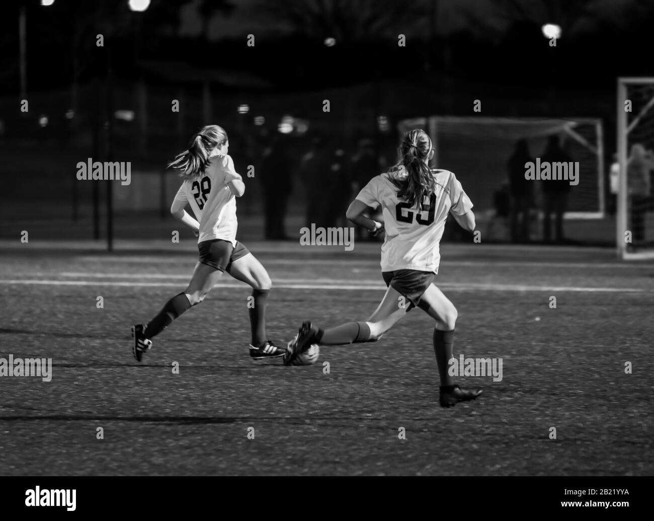 Two girls playing soccer run with a ball Stock Photo - Alamy
