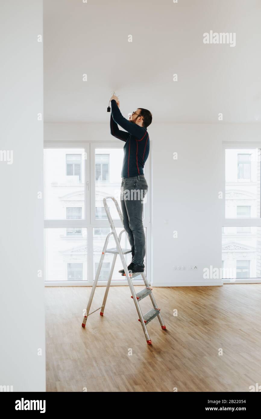 home owner standing on ladder fixing light installation Stock Photo - Alamy