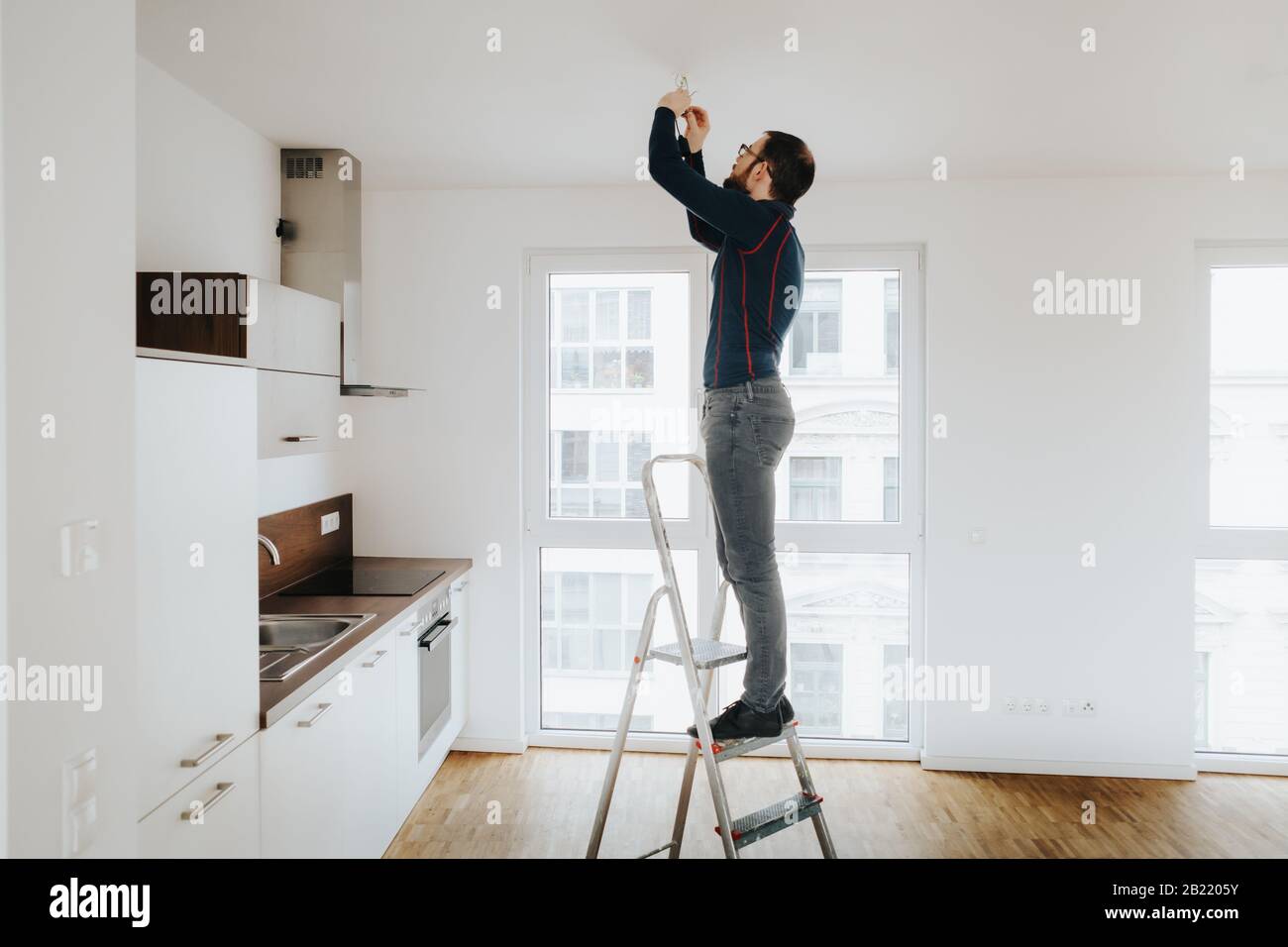 home owner standing on ladder fixing light installation Stock Photo - Alamy