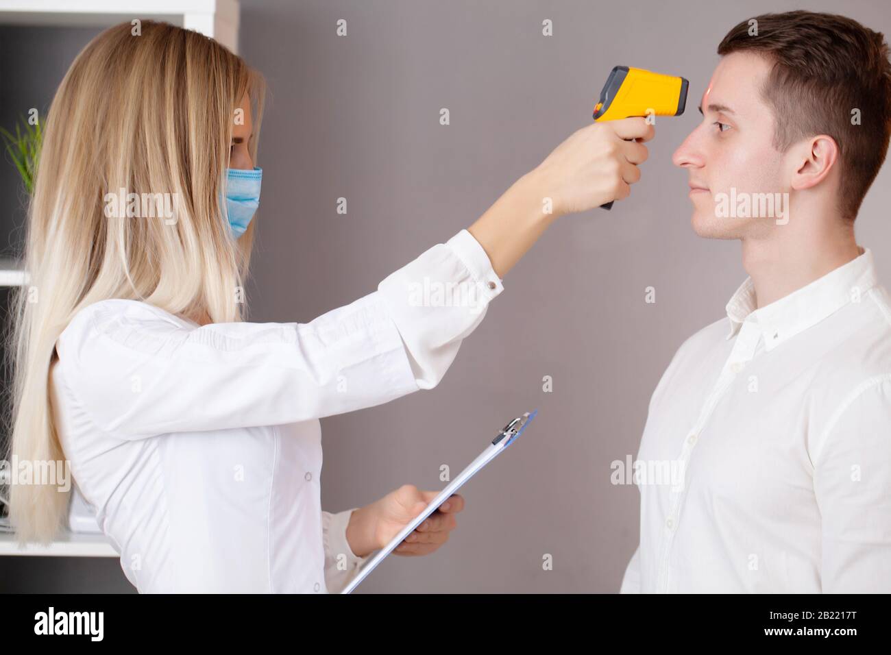 Doctor measures the patient's temperature with a laser thermometer ...