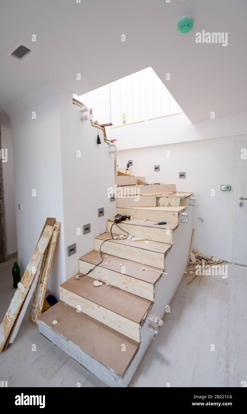 work in progress on stylish interior with wooden stairs in big modern ...