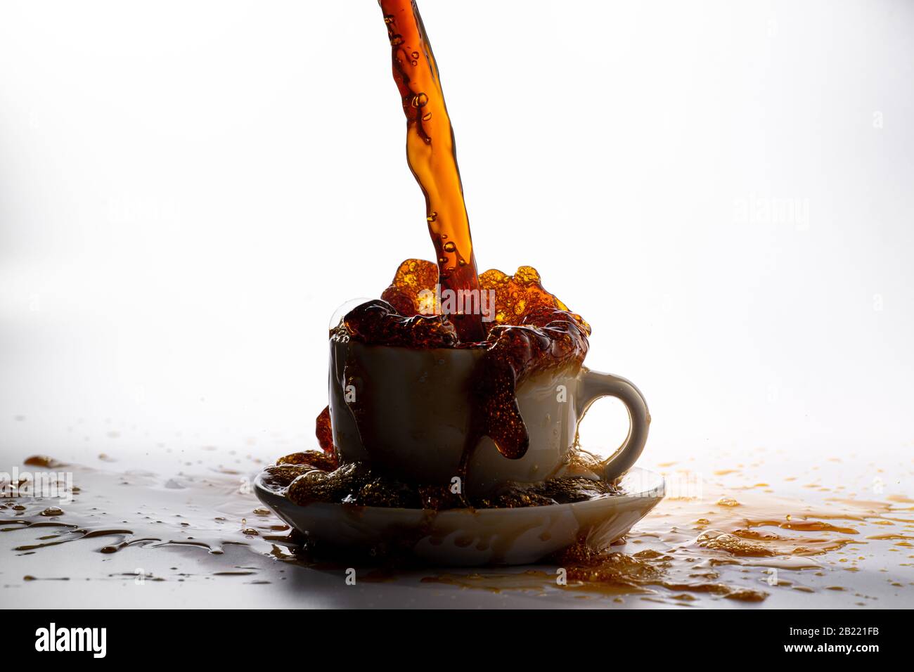 Coffee pouring into a white cup isolated against a plain white ...